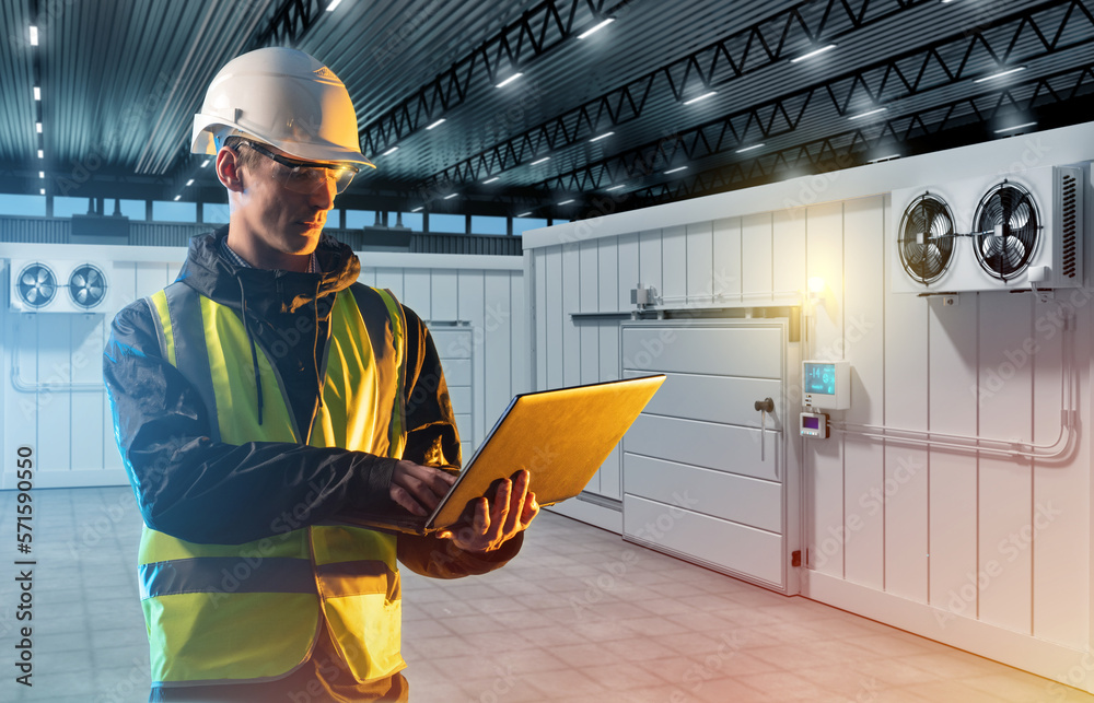 Man with laptop near freezer. Guy is testing work of refrigerators ...