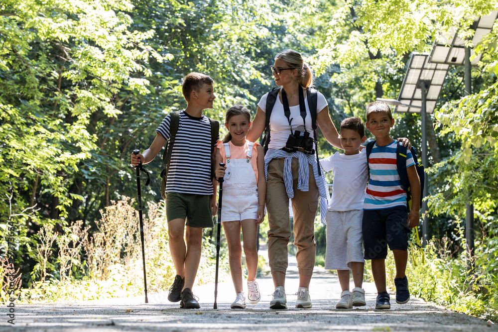 School kids hiking at the park with they teacher.They're learning about ...