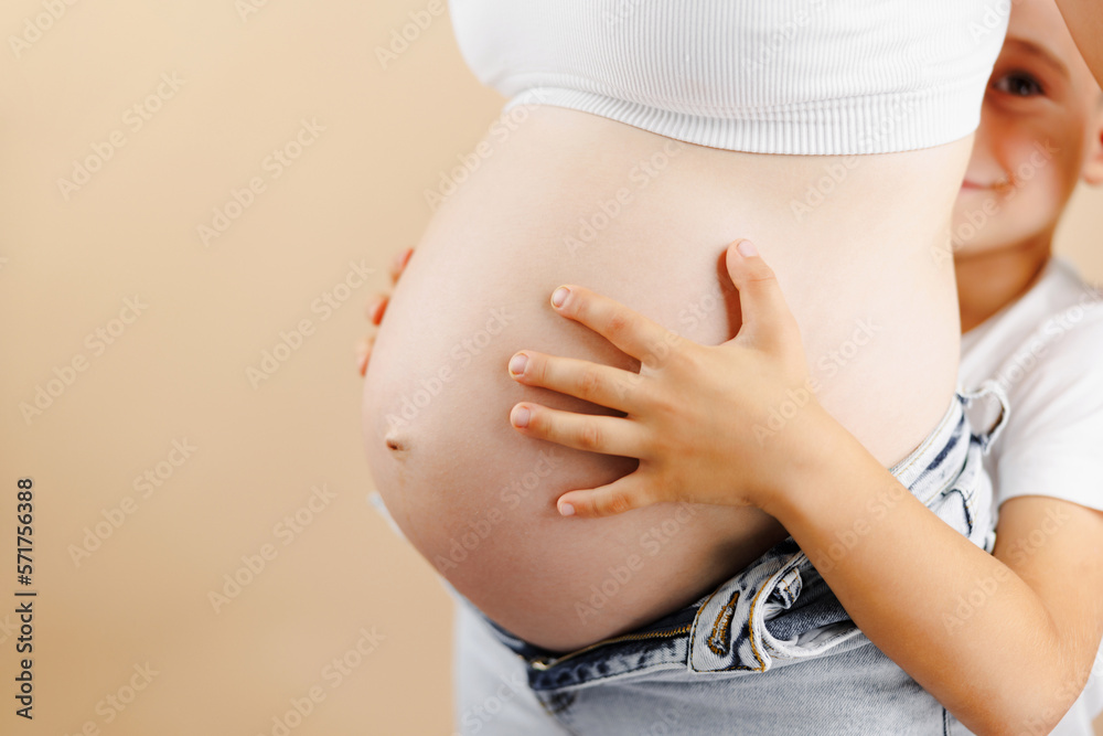 Lovely daughter touching mother's pregnant belly. Happy little girl ...