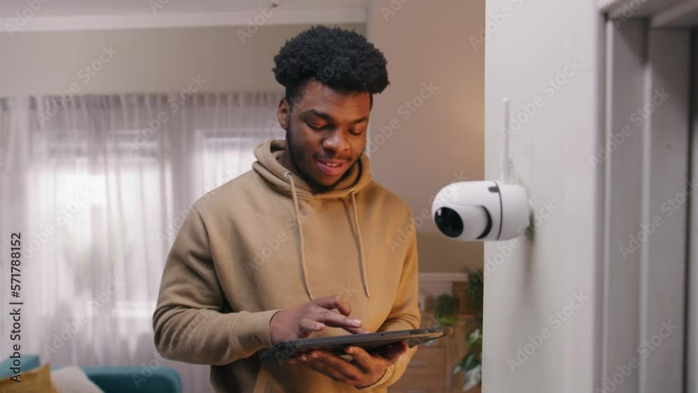 African American man installs security camera. Man sets up angle of ...
