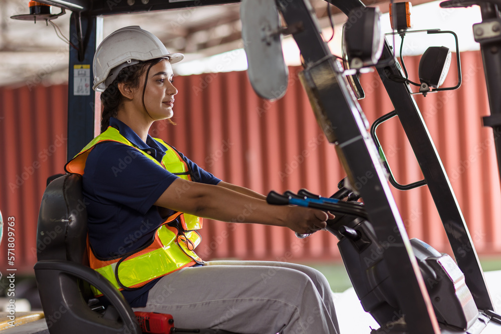 Indian woman staff worker work forklift driver at port cargo warehouse ...