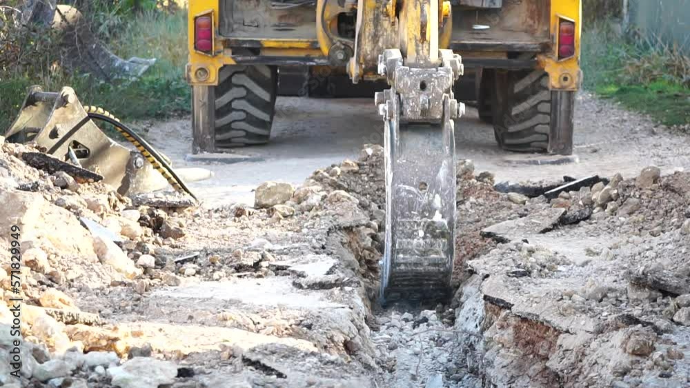 Excavator digs a trench to lay pipes. Close up of an excavator digging ...