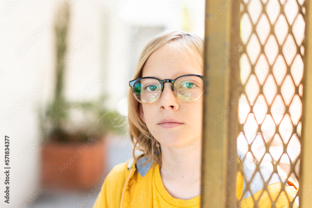 Portrait of tween looking around corner of gate wearing glasses Stock ...