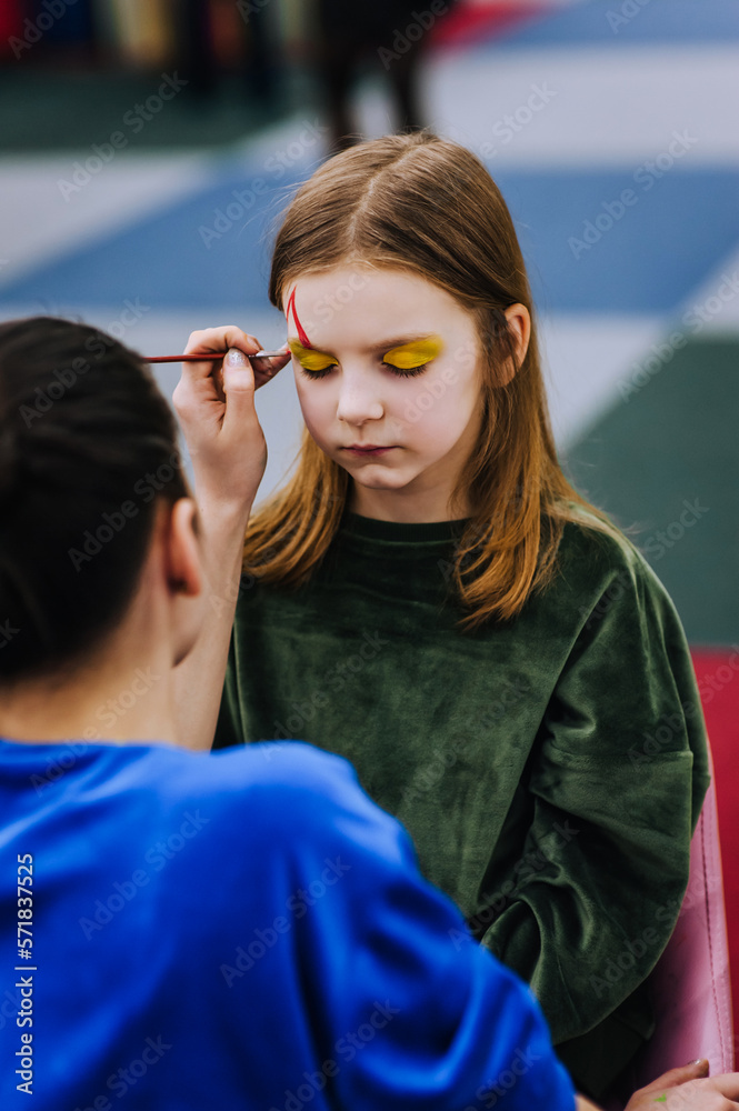 A professional make-up artist, artist paints with a brush on her face ...