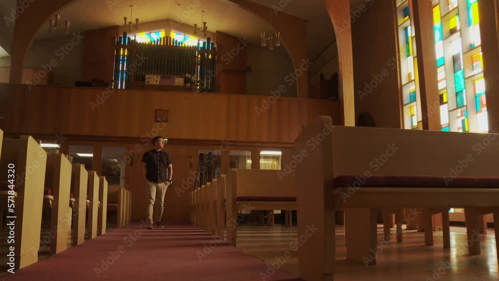 Wide shot ethnic male walking down a church aisle in a sanctuary ...