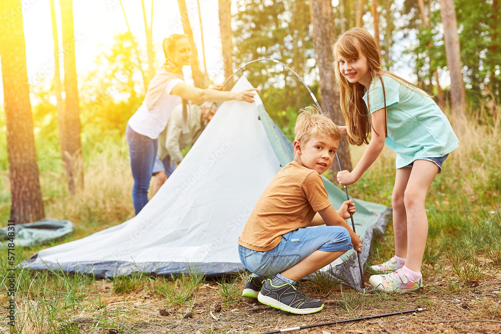 Siblings helping parents setting up tent while family camping Stock ...