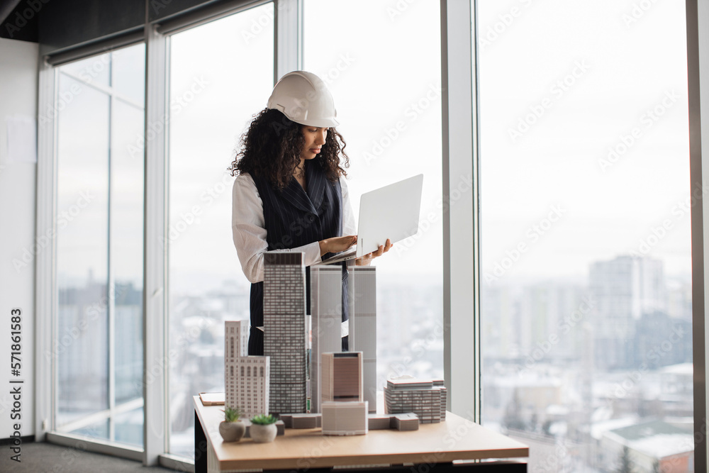 Attractive young woman architect in business suit and white protective ...