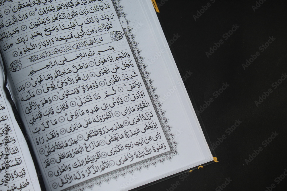 An opened page of the Holy Quran showing Surah An najm. A letter in the ...