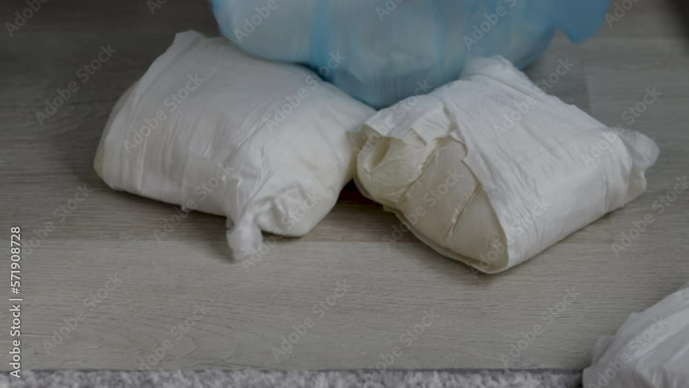 many dirty full baby diapers on floor bed or in blue trash plastic bag ...