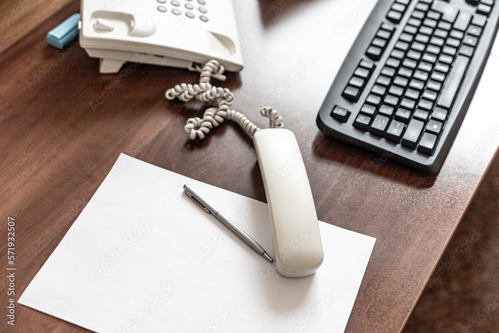 Office work. A phone, keyboard, pen and a blank sheet of paper on the ...