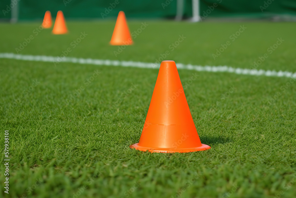 Football training cone aligned on artificial grass pitch, ready for dribbling and movement ...