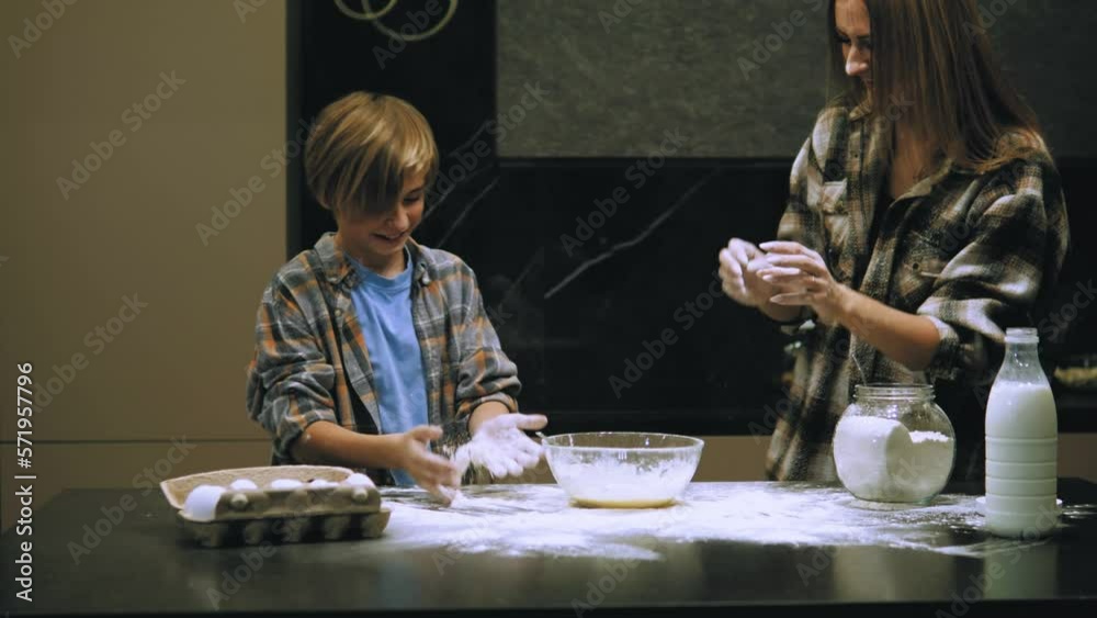 Happy cheerful mom and son giving five each other while cooking a cake ...