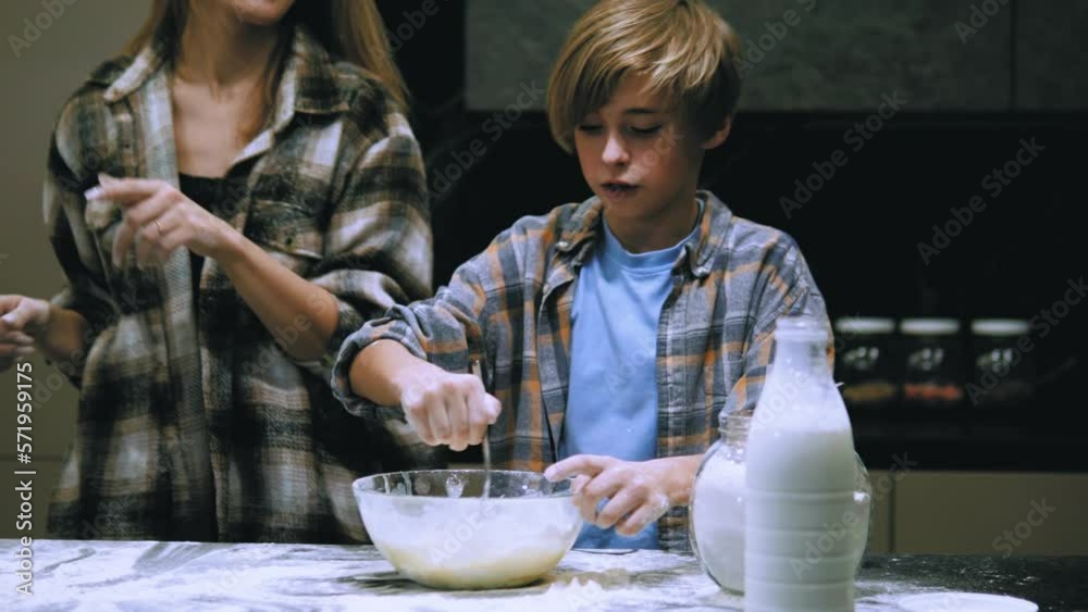 Excited boy kneading dough, mixing with spoon, cooking preparing a ...