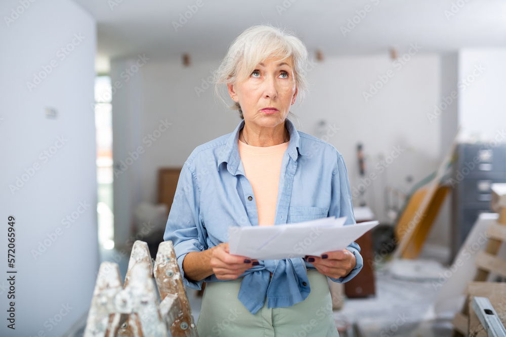 Disappointed senior female designer examining room at renovating object ...