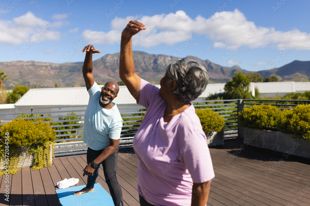 African american senior couple performing stretching exercise on the ...