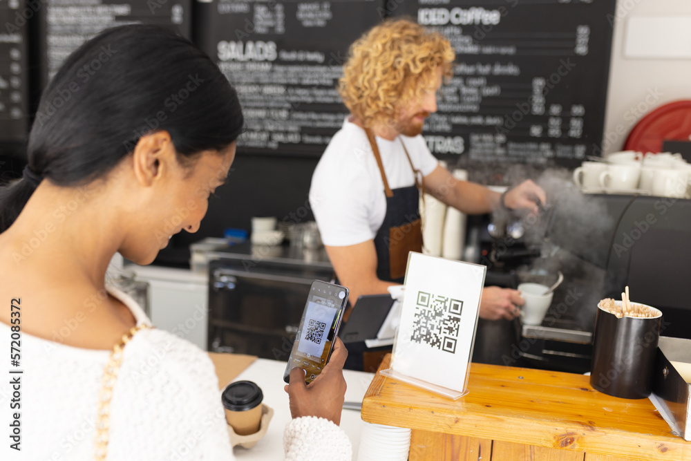 Happy diverse male barista and woman scanning qr code with smartphone ...