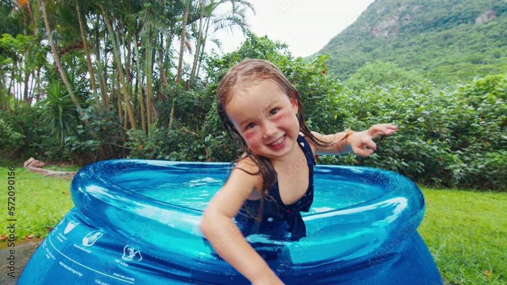 Girl in the pool. Girl has fun in the inflatable pool set in the green ...