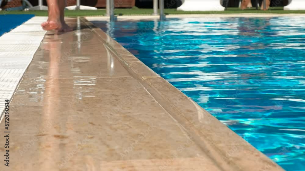 Test pool water with hand. A girl with barefoot testing the swimming ...