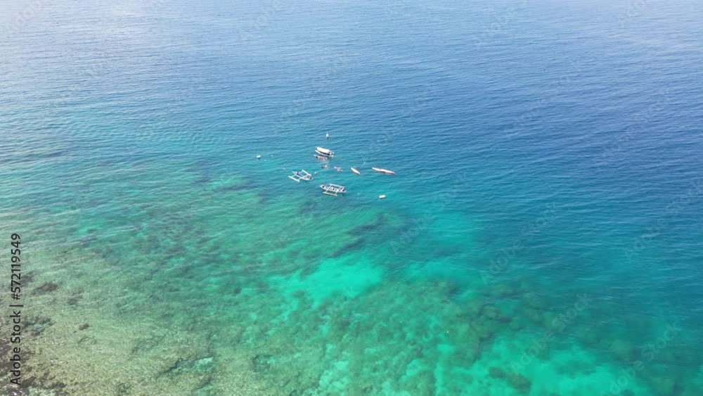 Top view of clear ocean turquoise water and a small cluster of boats ...