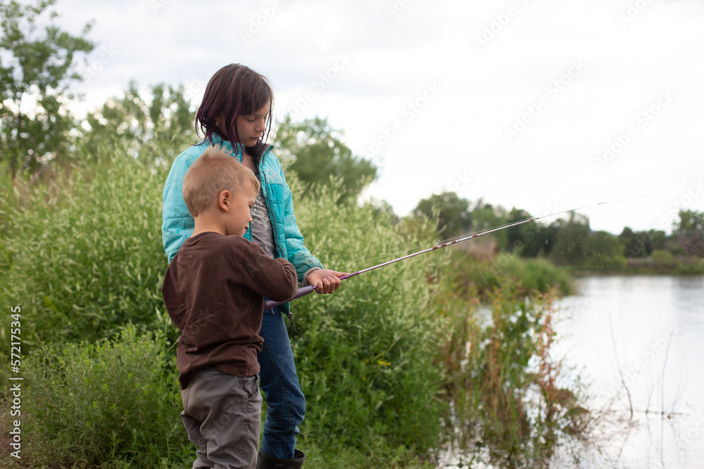 Siblings fishing at a pond, sister helping little brother Stock Photo ...