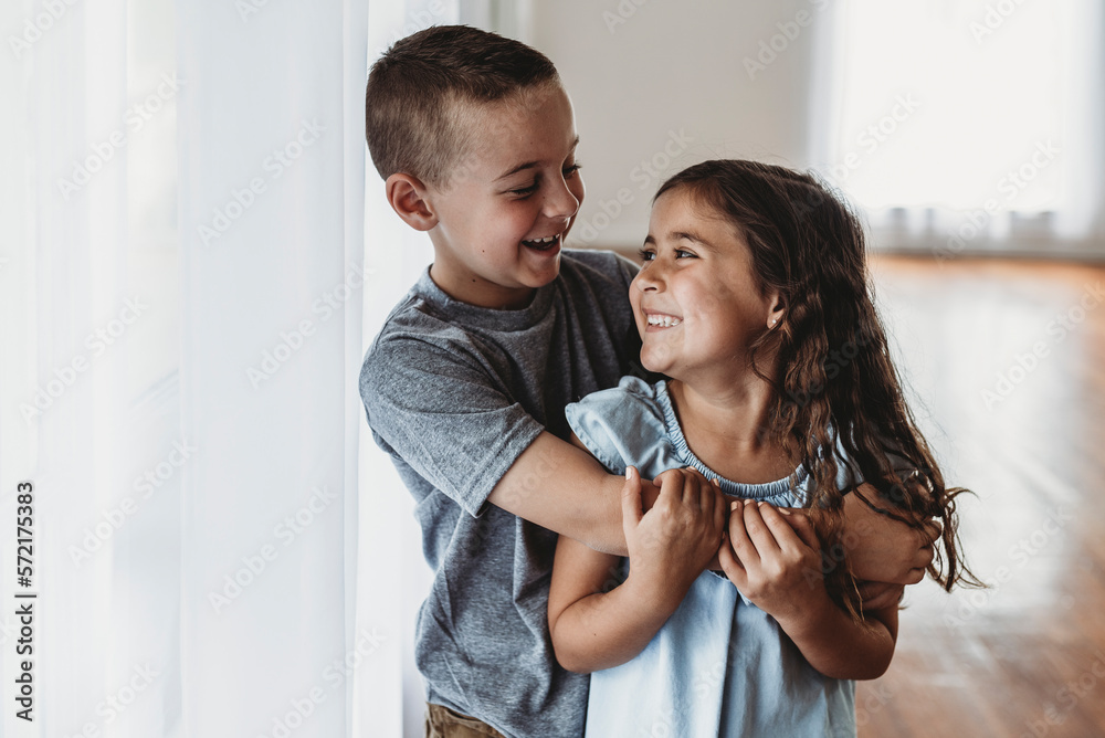 Brother and sister laughing at each other in natural-light studio Stock ...