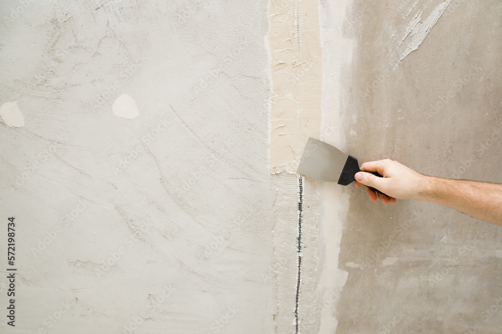 Young adult man hand using spatula and plastering concrete ceiling or ...