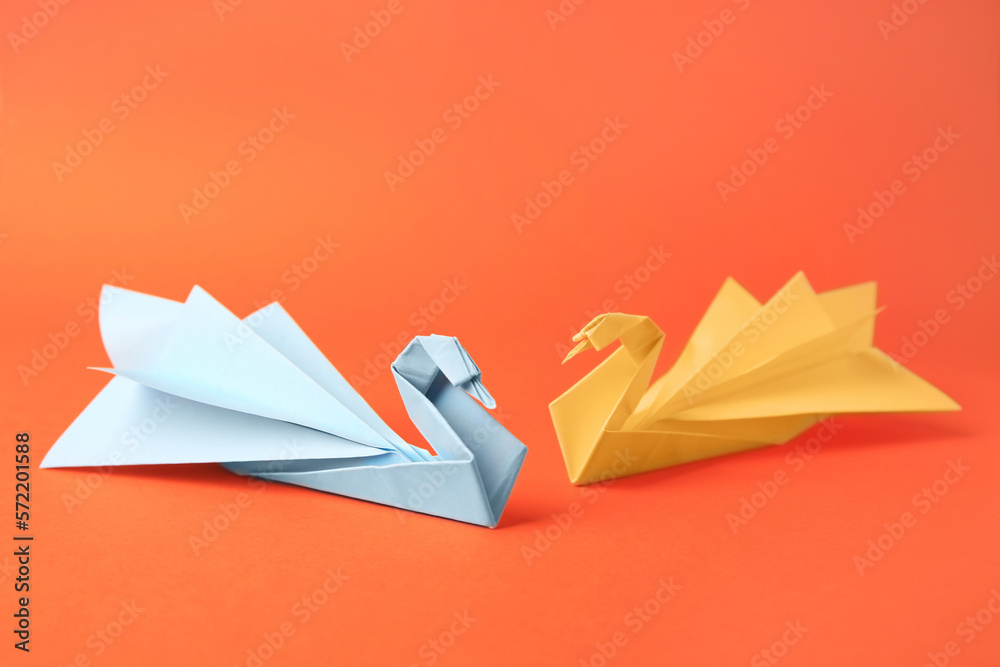 Origami art. Beautiful paper swans on orange background Stock Photo ...