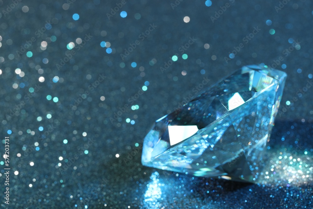 Beautiful dazzling diamond on light blue glitter background, closeup ...