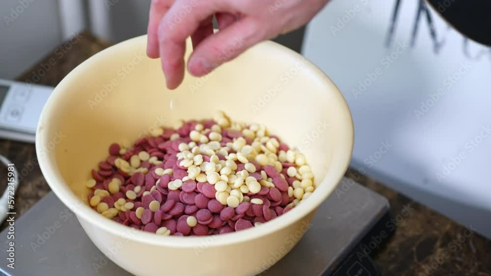 Unrecognisable chocolatier pouring white chocolate callets into bowl ...