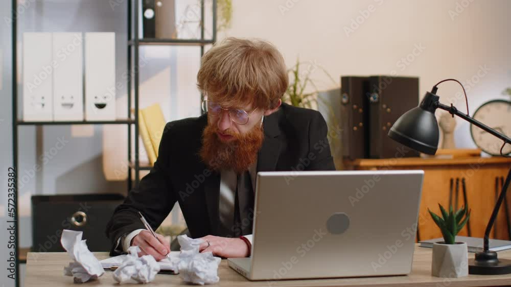 Angry furious young man working at office throwing crumpled paper ...