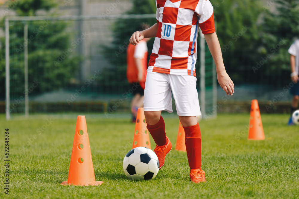 Happy young boy in red and white soccer uniform on training drill ...