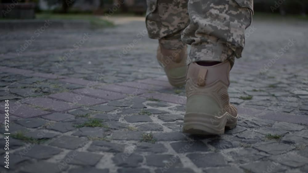 Legs of young man in military uniform walking slowly down the street on ...