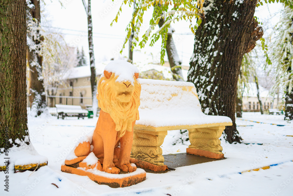 Snow on the lion sculpture in the park. Winter background, selective ...