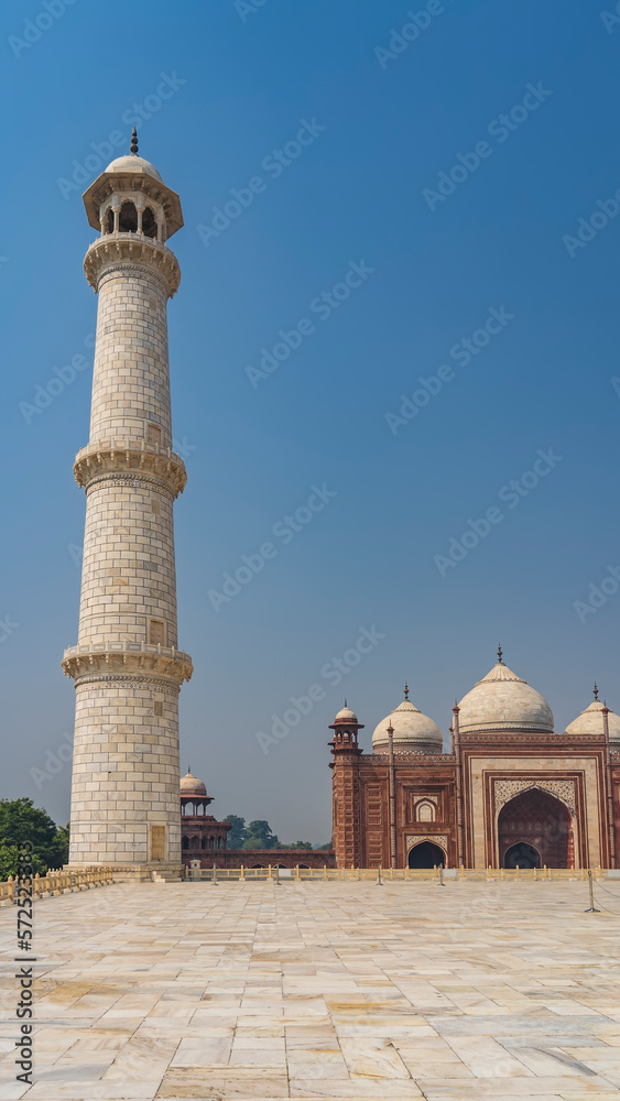 The tall white marble minaret of the ancient mausoleum of the Taj Mahal ...