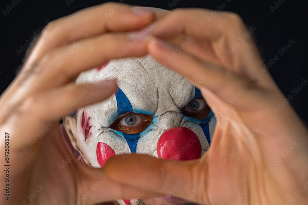 The face of a man wearing a scary clone mask through clenched palms ...