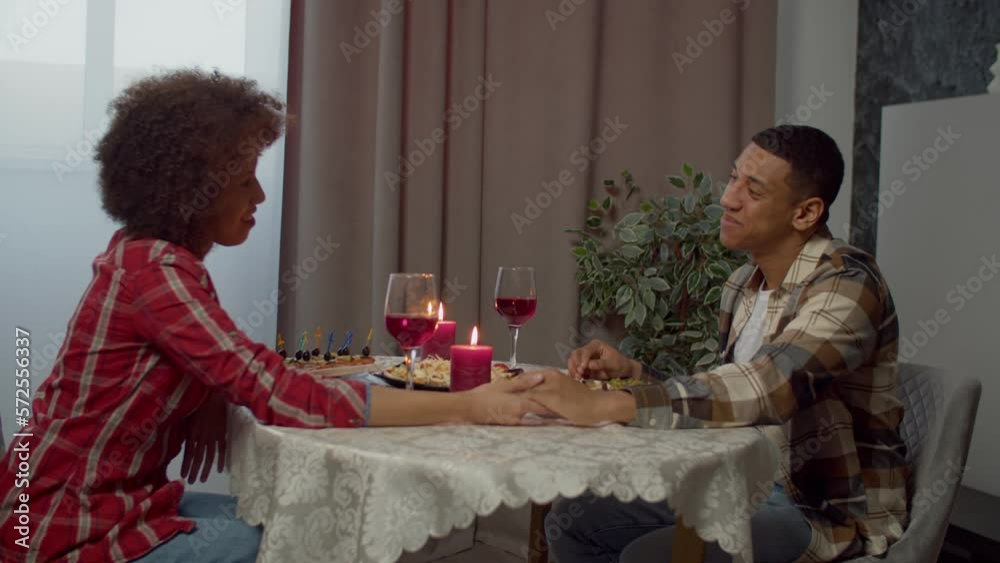Affectionate attractive black couple enjoying dinner in candlelight ...