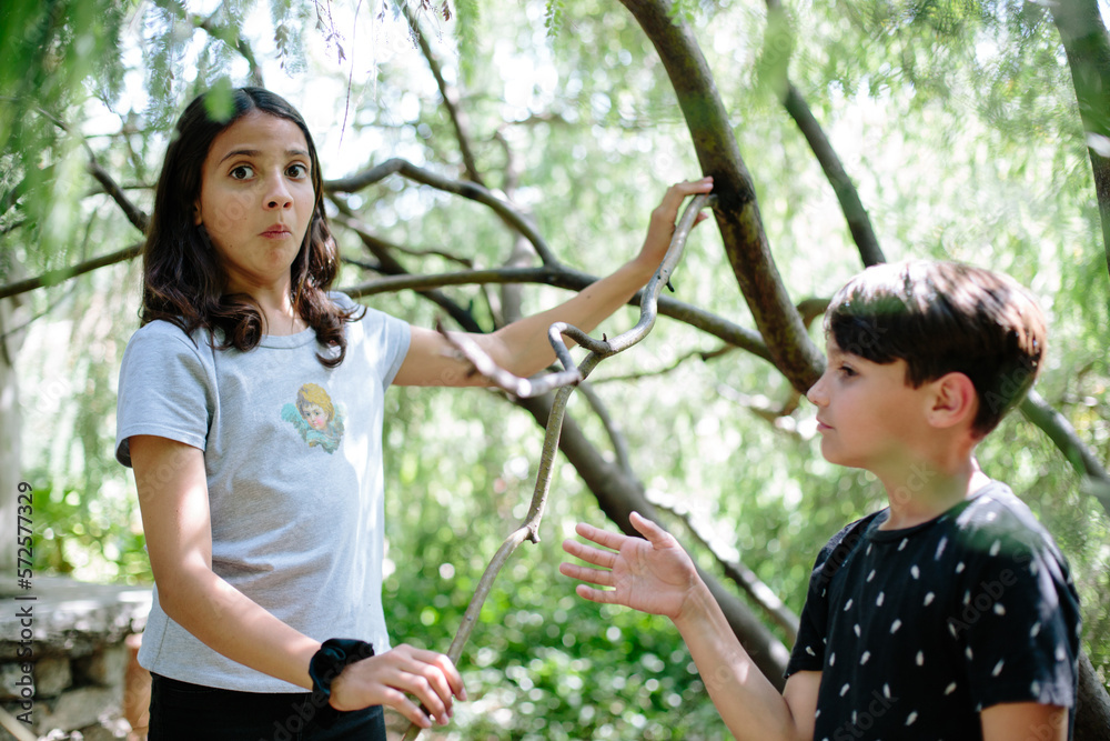 Tween girl looks as if she's in trouble while holding onto tree branch ...