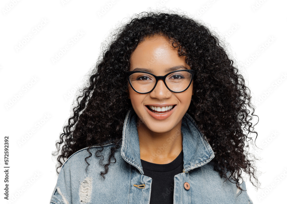 Glad woman with curly hair, wears optical glasses, denim jacket, looks ...