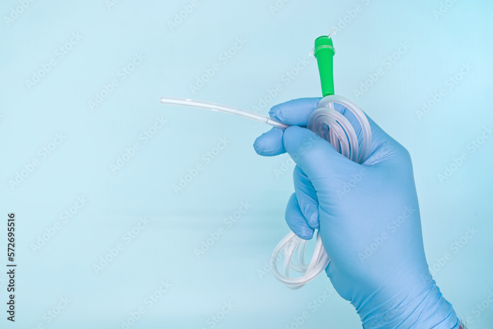 hand in medical glove holding nasogastric tube on blue background. Stock Photo | Adobe Stock