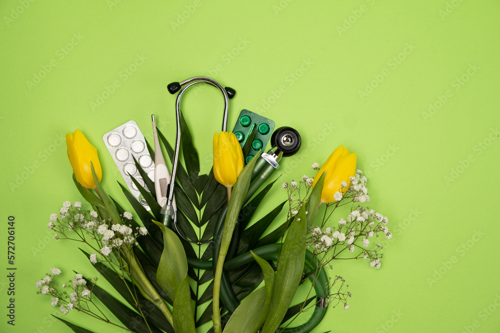 Bouquet of flowers and stethoscope on a green background, a place for ...