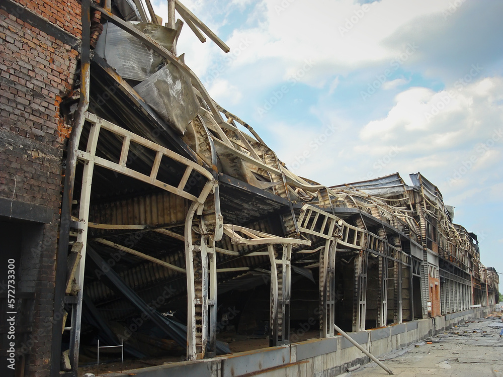 A warehouse with a loading ramp after a fire. Burnt metal frame of the ...