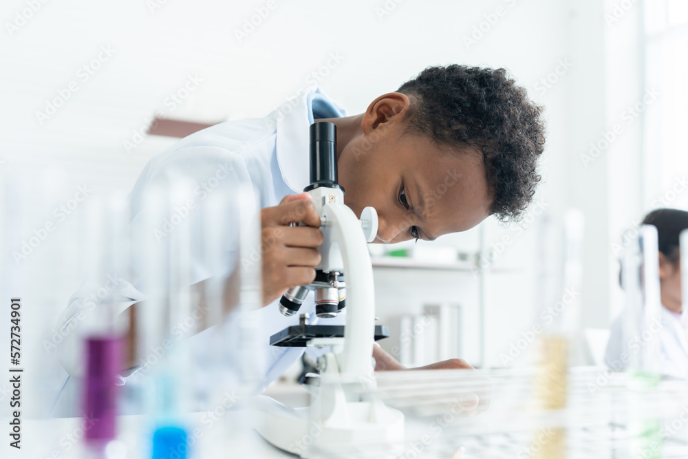 little african boy is paying attention to the microscope in the science ...