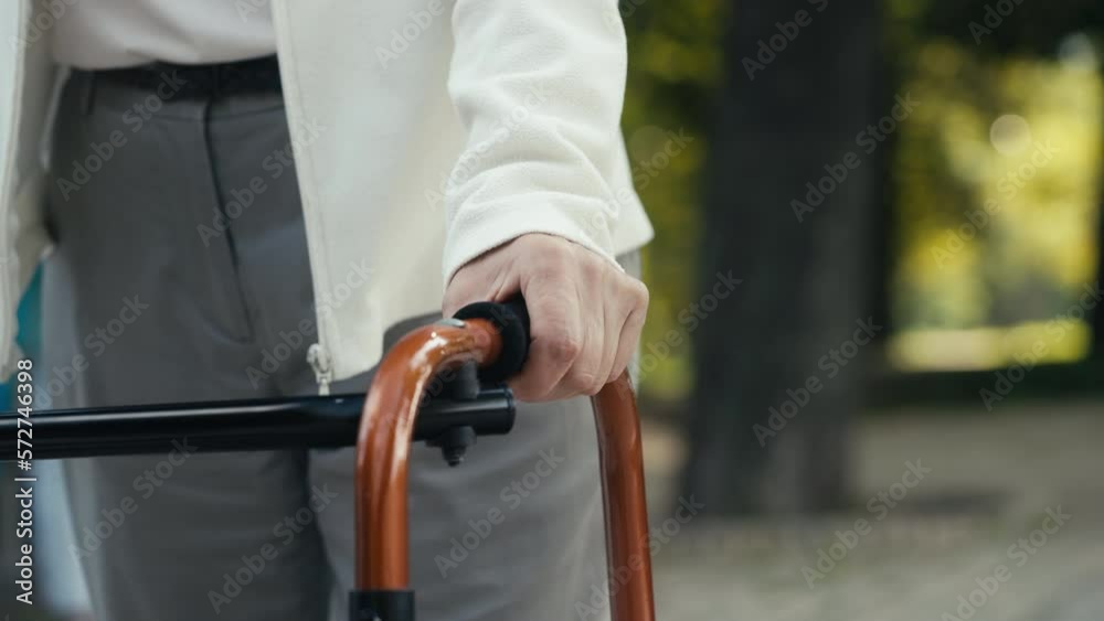 Elderly person using walking frame to walk in a park, senior age health ...