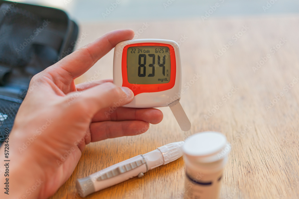 young man using blood test kit at home while doing health check . home ...