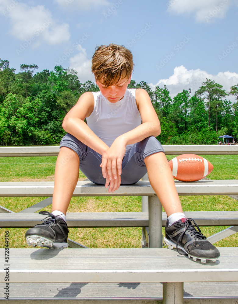 Youth Preteen Boy Football Player Sitting on the Bleachers with ...