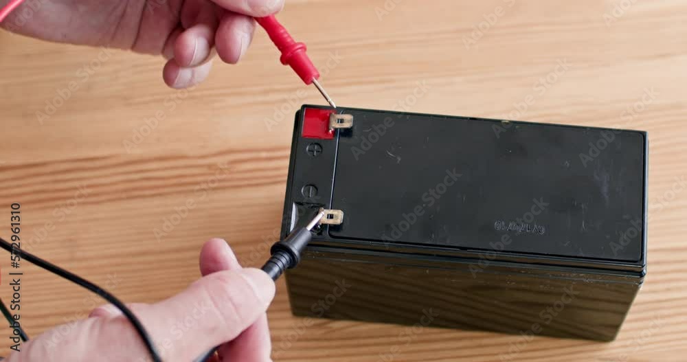 Close-up, a person brings black and red multimeter probes to the ...