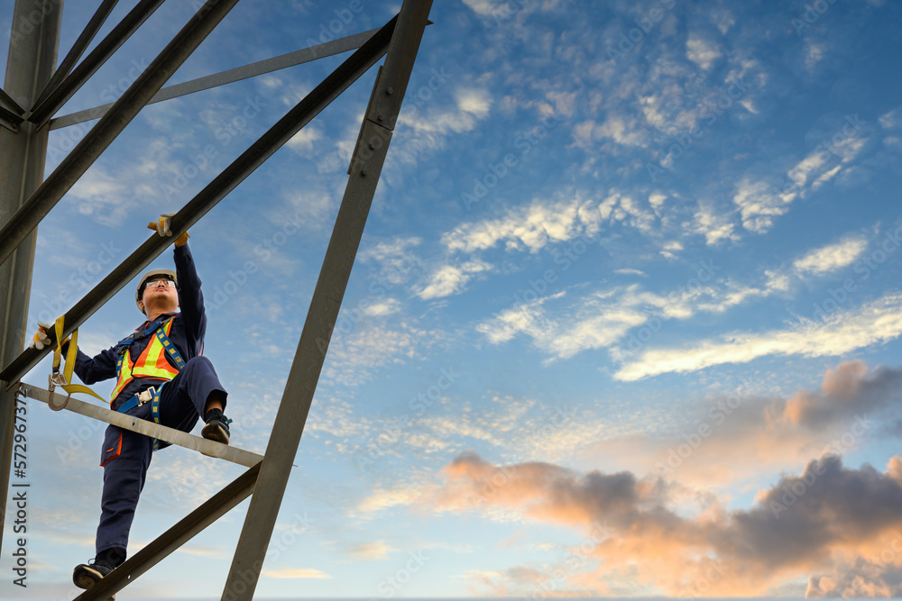 Asian male electrician worker climbs high-voltage pylons at a power ...