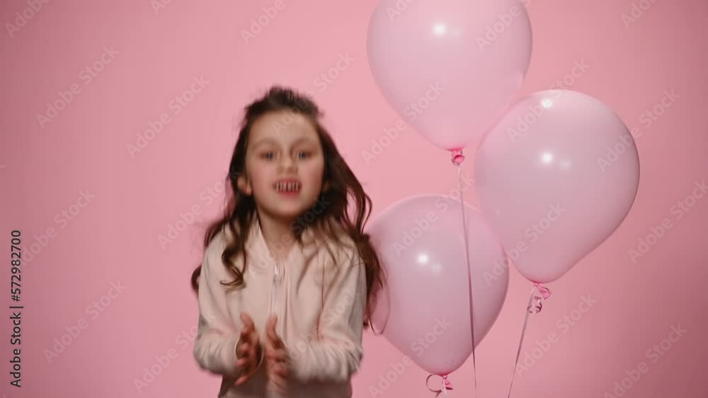 Lovely cheerful little girl in pink pastel wear, clapping her hands and ...