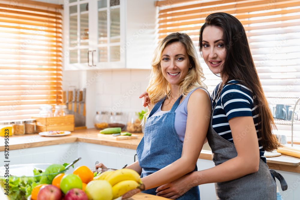 Foto de An LGBTQ caucasian couple is cooking together in the kitchen in ...