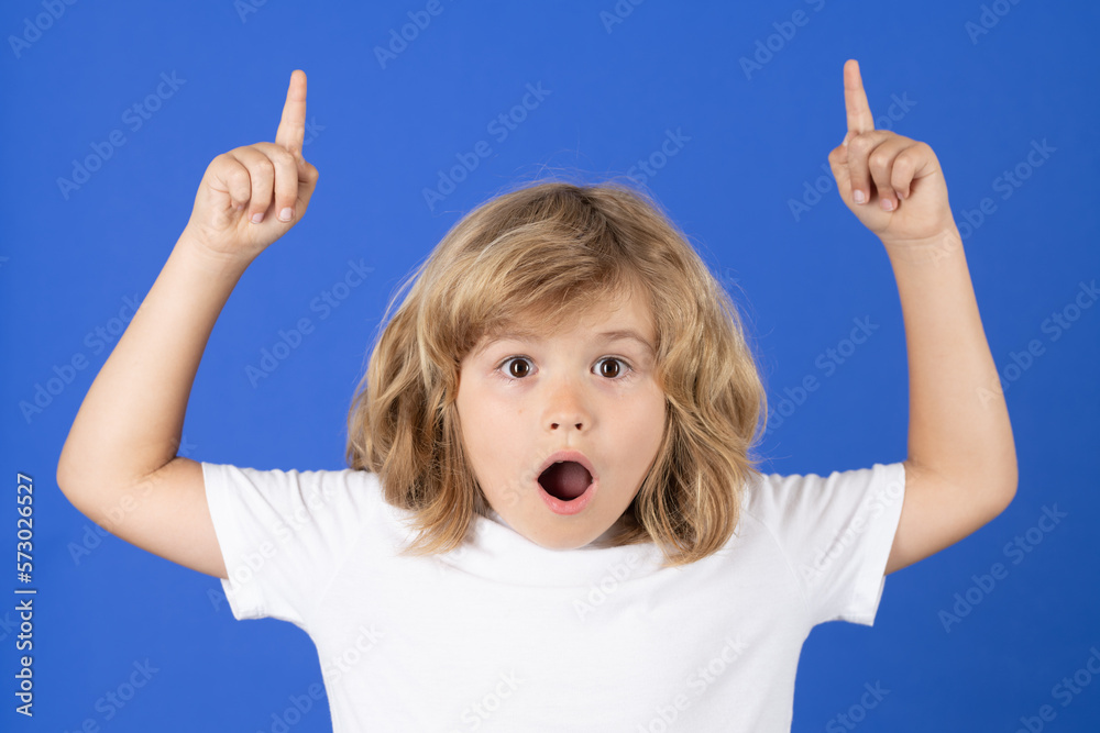 Surprised child pointing up finger on blue studio background. Shocked ...